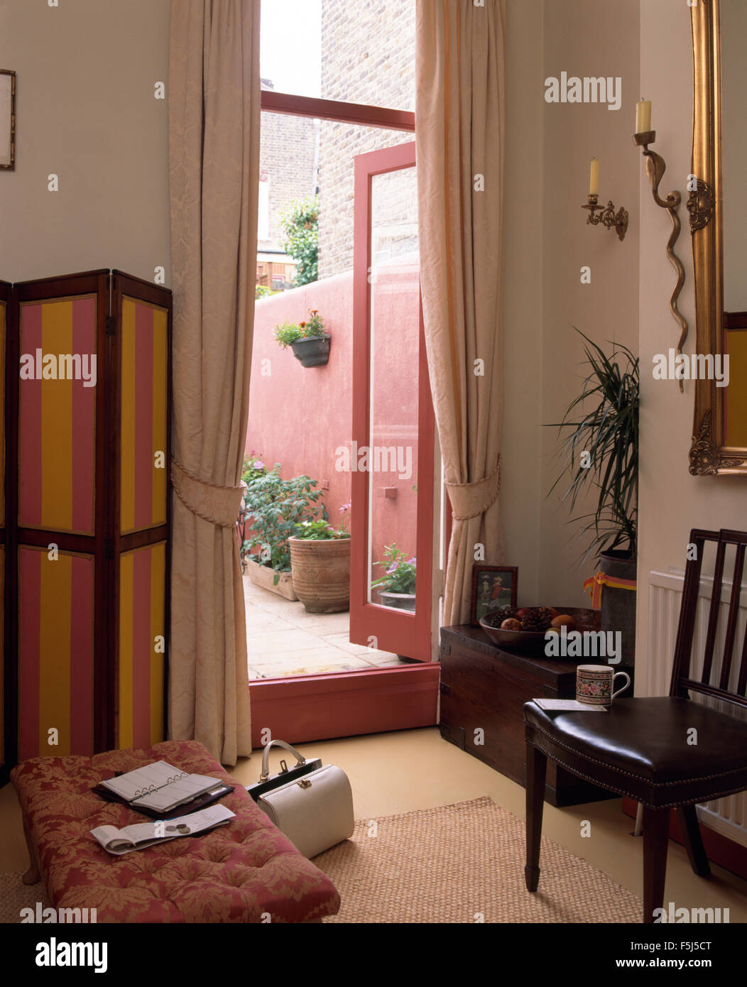 Striped folding screen beside French windows in nineties living room ...