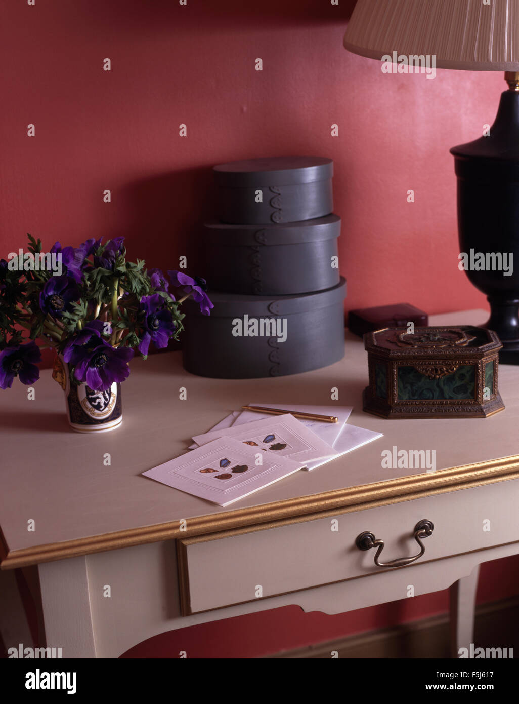 Vase of blue anemones and stack of Shaker boxes on a painted table ...