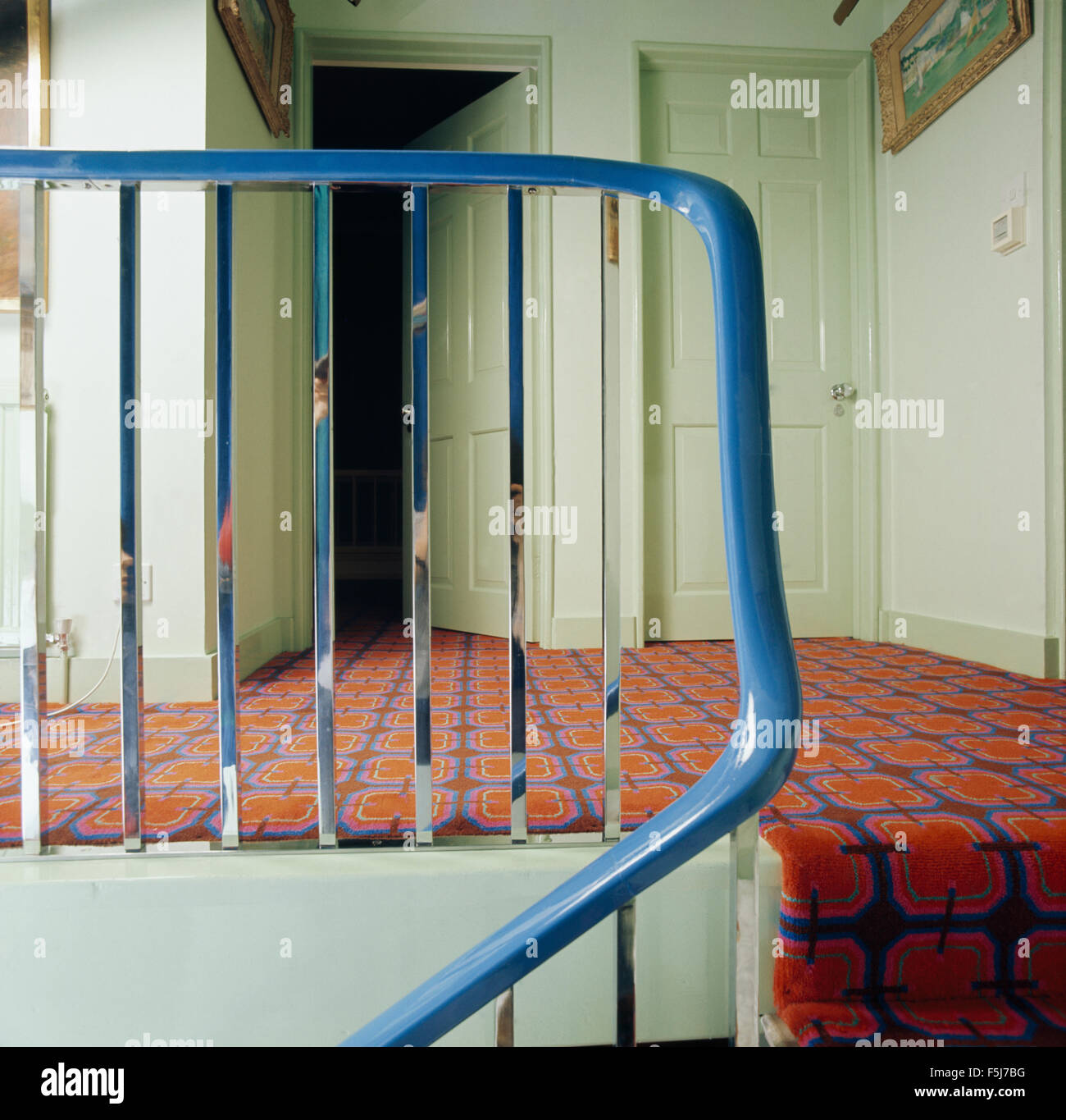Blue metal handrail on banister on seventies landing with a vibrant red ...
