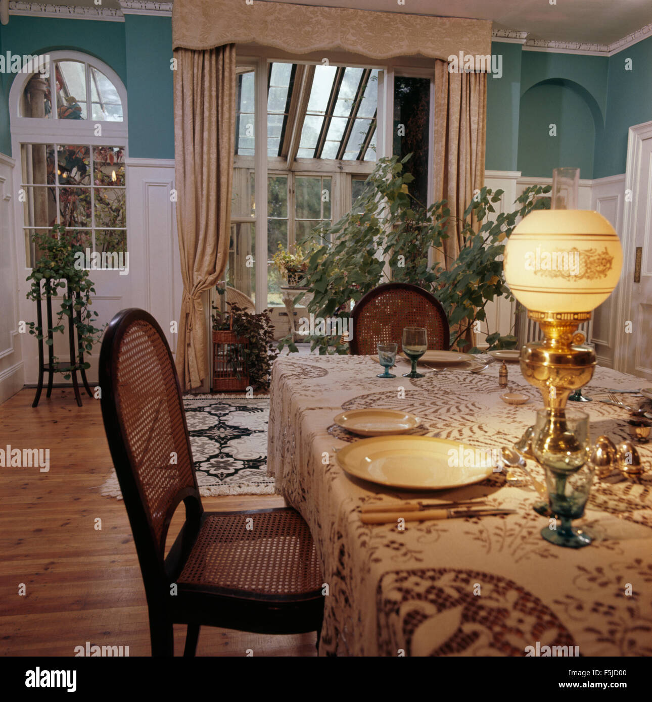 Edwardian style glass and brass lamp on table set for lunch with a lace ...