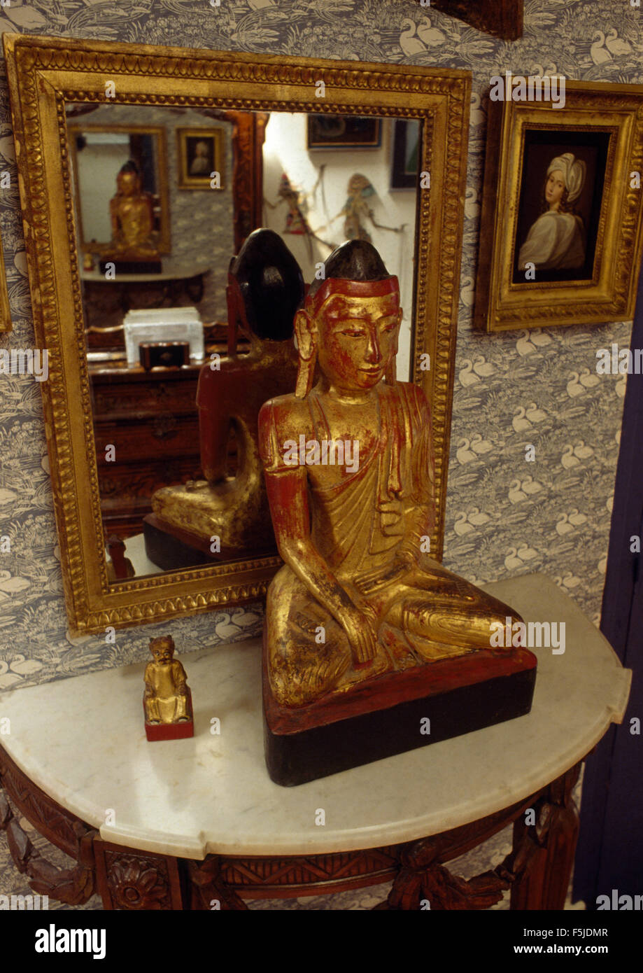 Gilt Asian statue on a marble topped console table in a sixties hall ...