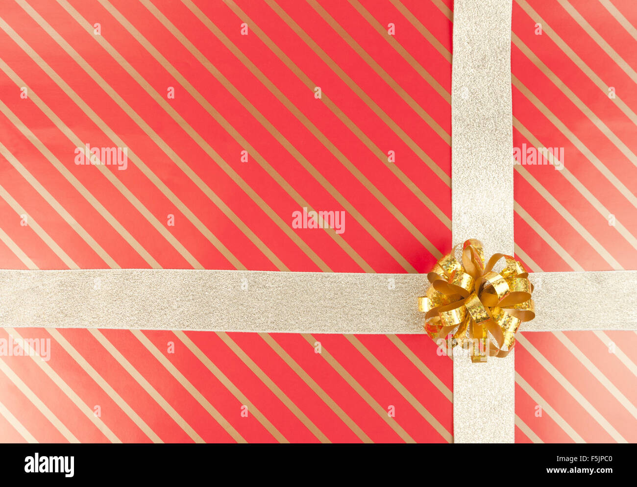 Gold ribbon and bow on striped red gift paper Stock Photo - Alamy