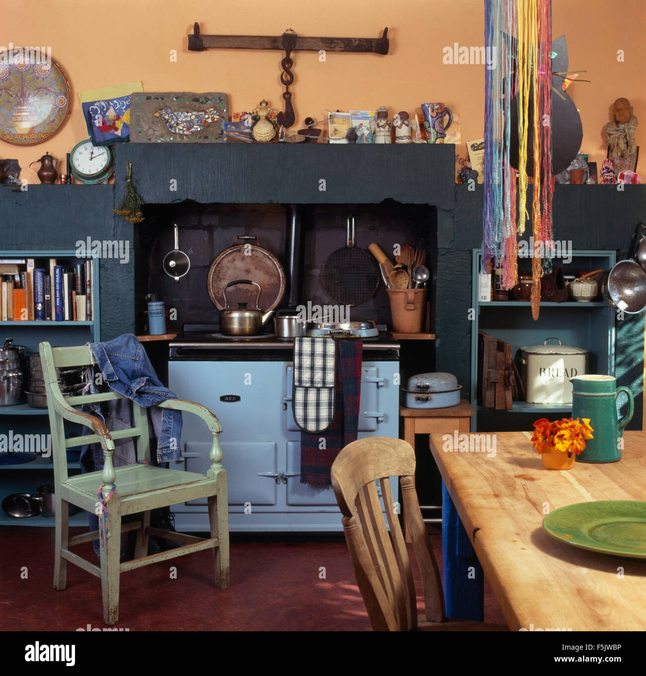 Painted wooden chair beside pale blue Aga in a nineties kitchen with a ...