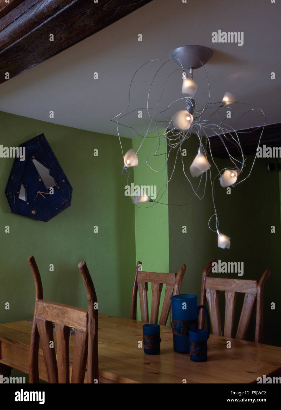 Twisted metal light fitting above wooden table and rustic chairs in a ...