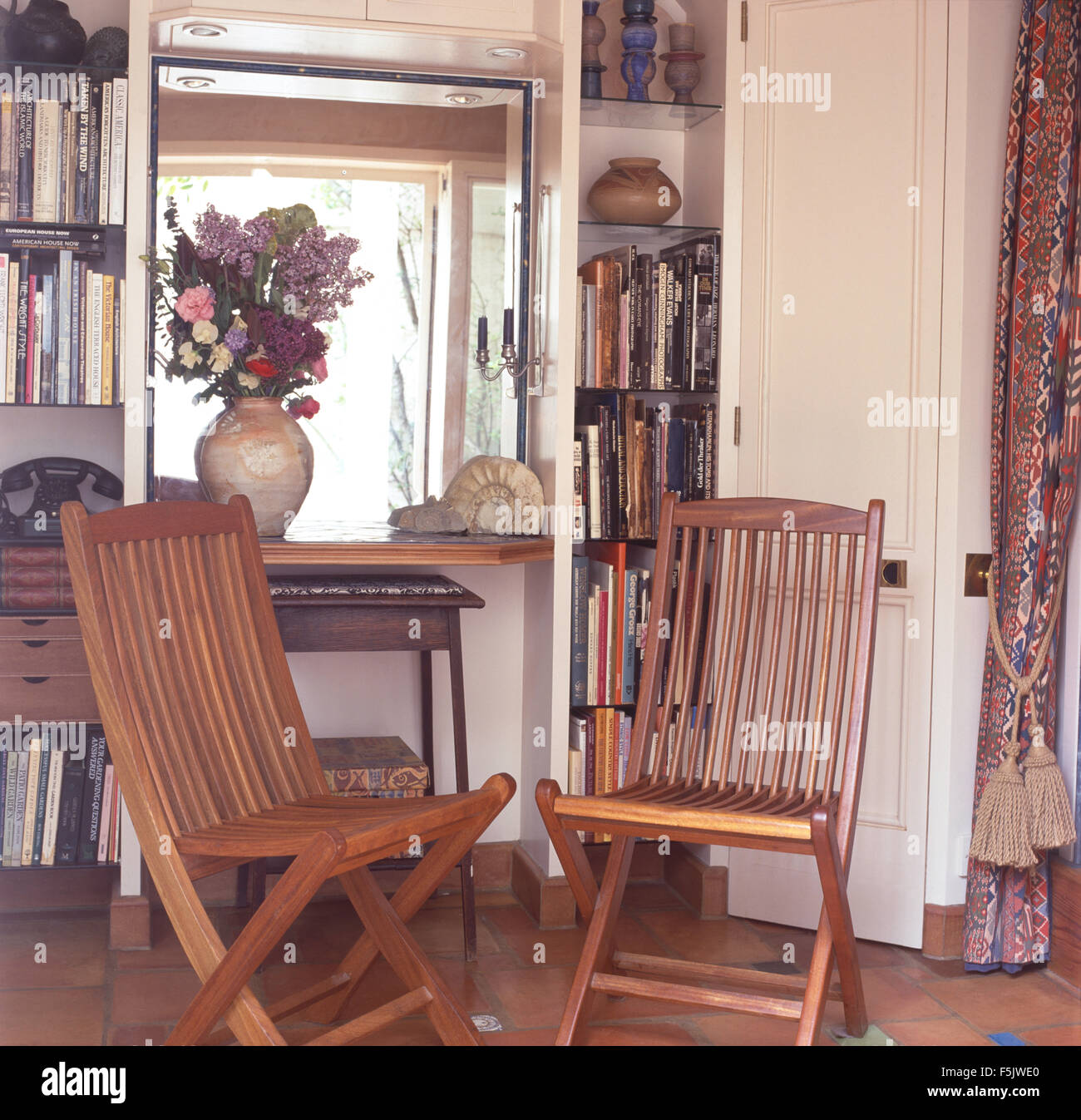 Slatted wooden chairs in front of a small window between narrow ...