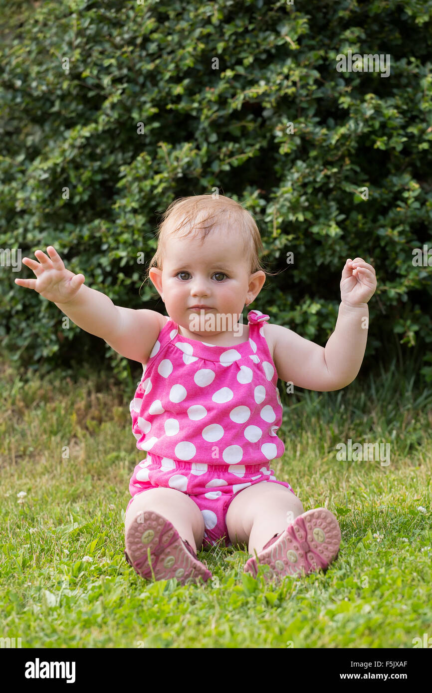 Happy cute little one year old girl outdoor, summer, with pink dress ...
