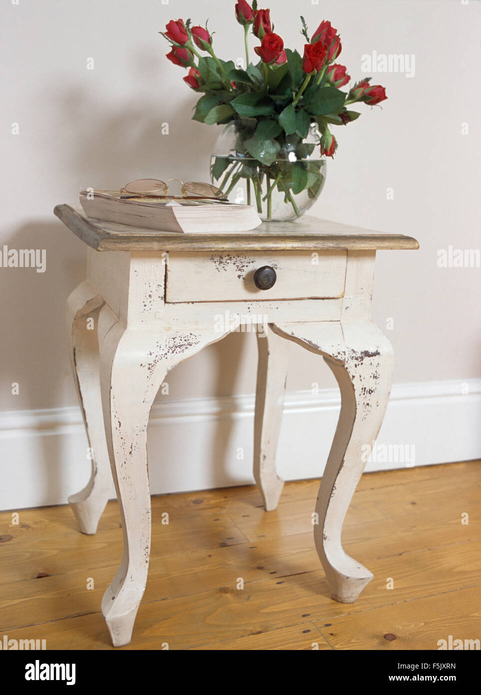Vase of red roses on a small white painted occasional table Stock Photo ...