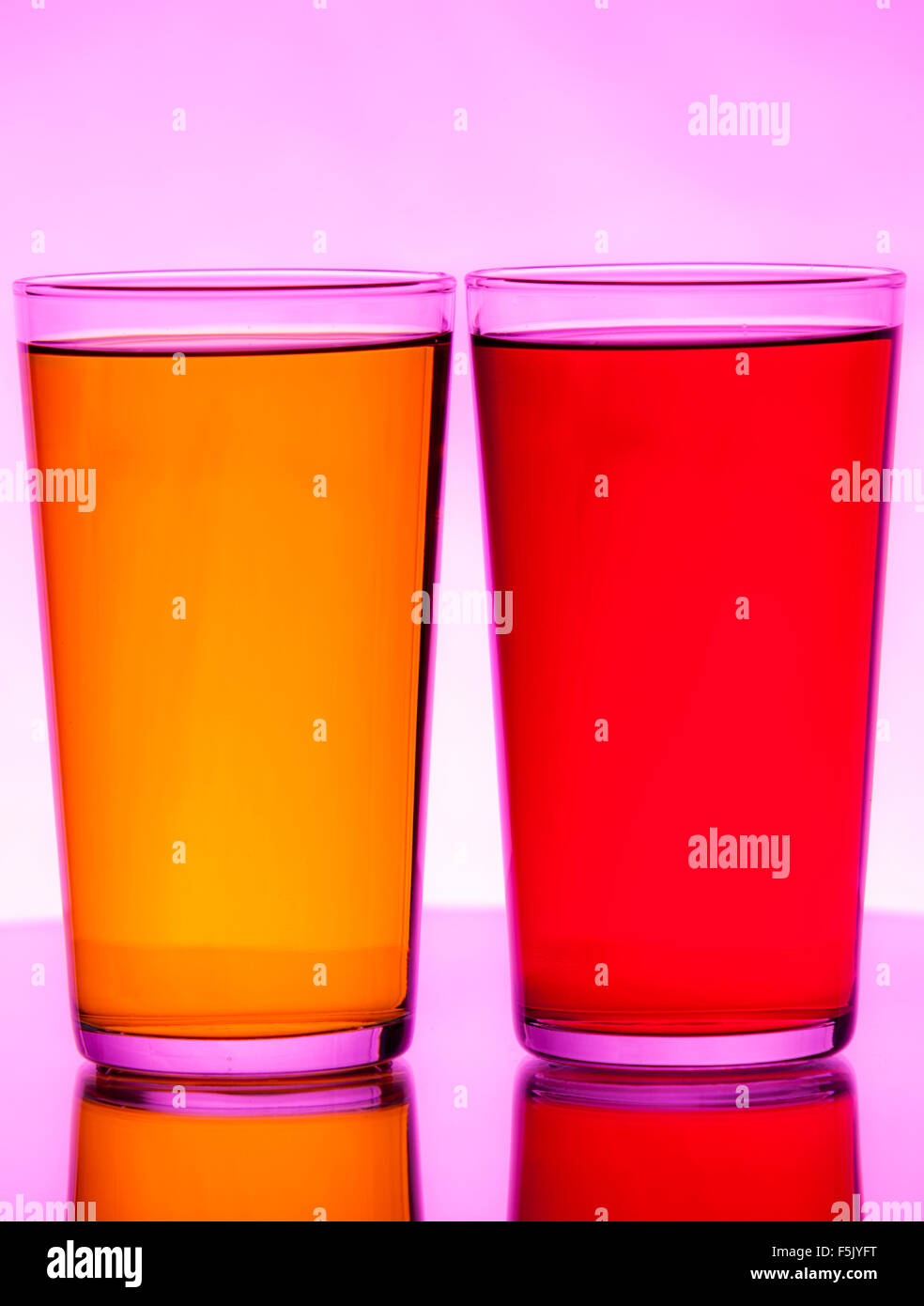 2 glasses containing coloured liquid against a coloured background ...