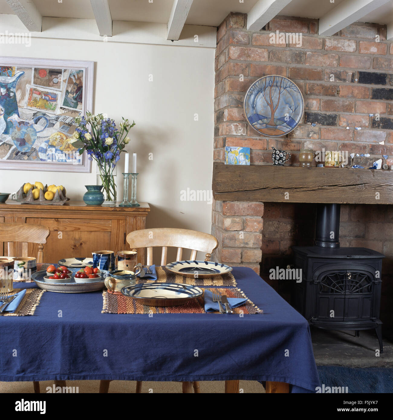 Blue cloth and rustic pottery plates on table set for lunch in a ...