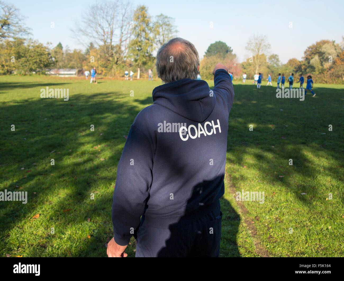 An amateur team football coach shouts instructions from the sideline of ...