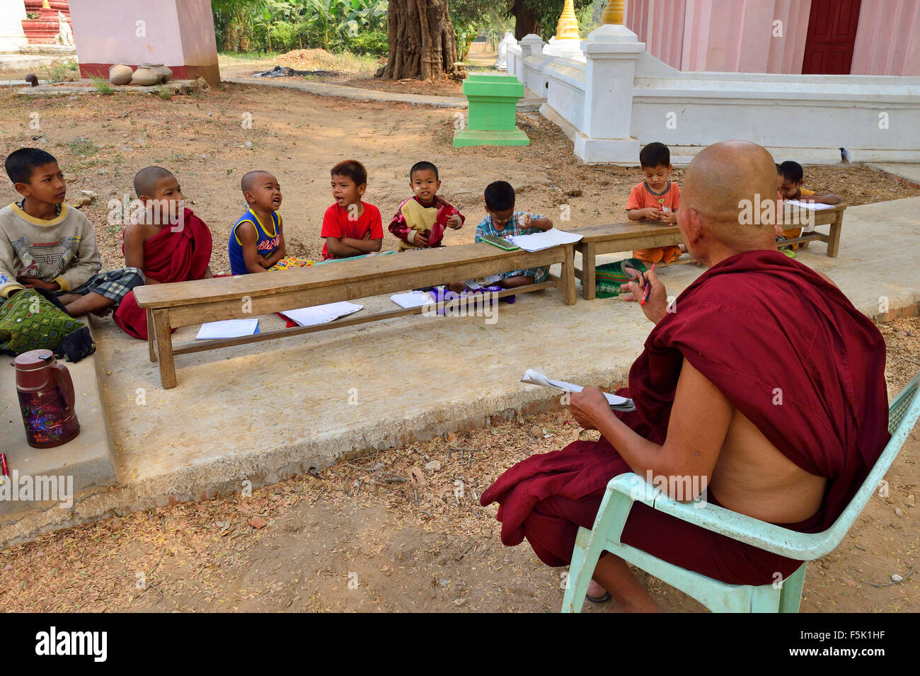 Buddhist Monk teaching schoolchildren lessons outdoors in the grounds ...