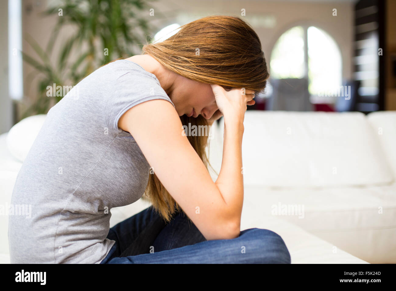 Sad woman sitting in the room Stock Photo - Alamy