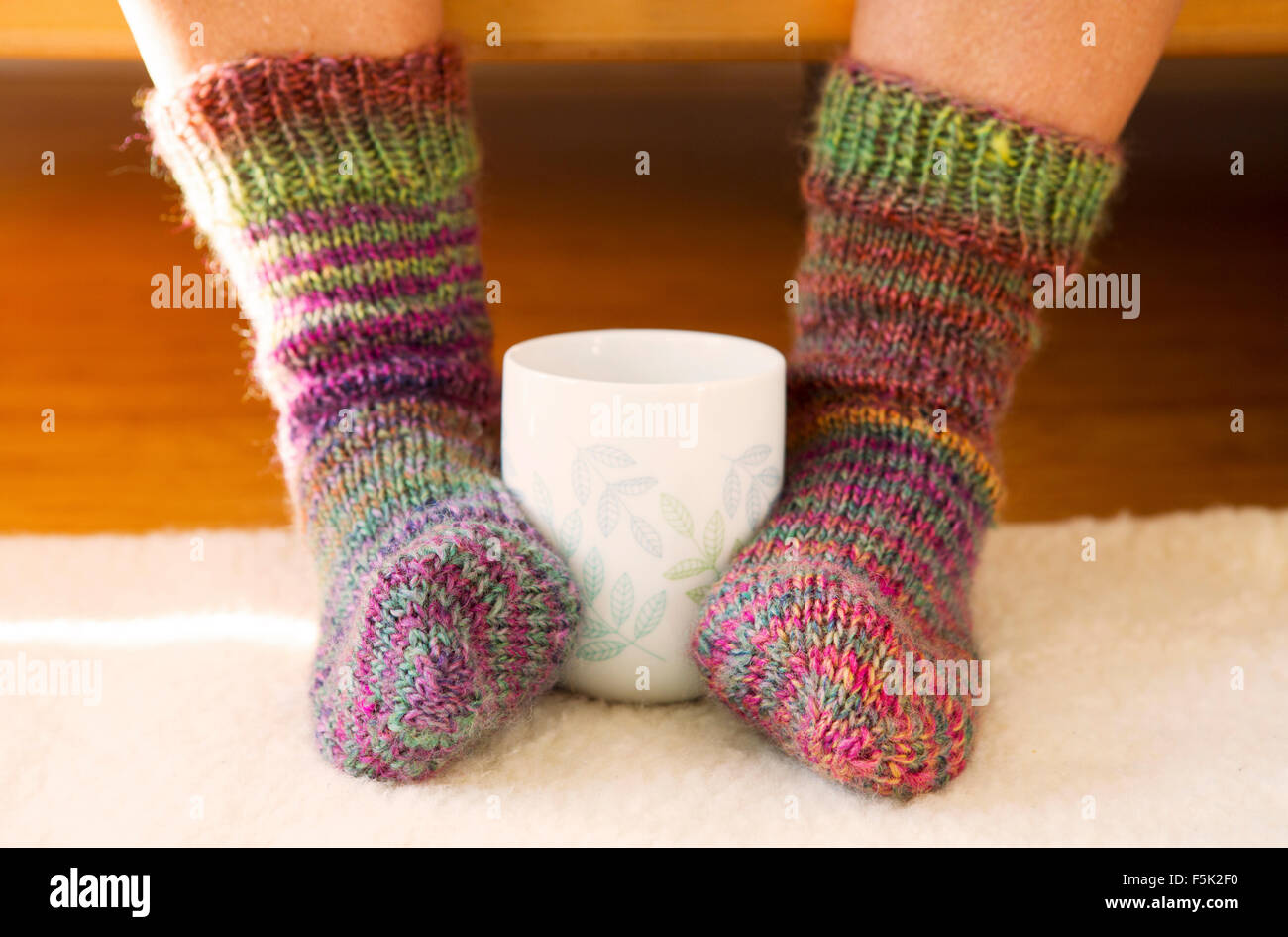 cup standing between two feet wearing knitted socks Stock Photo - Alamy