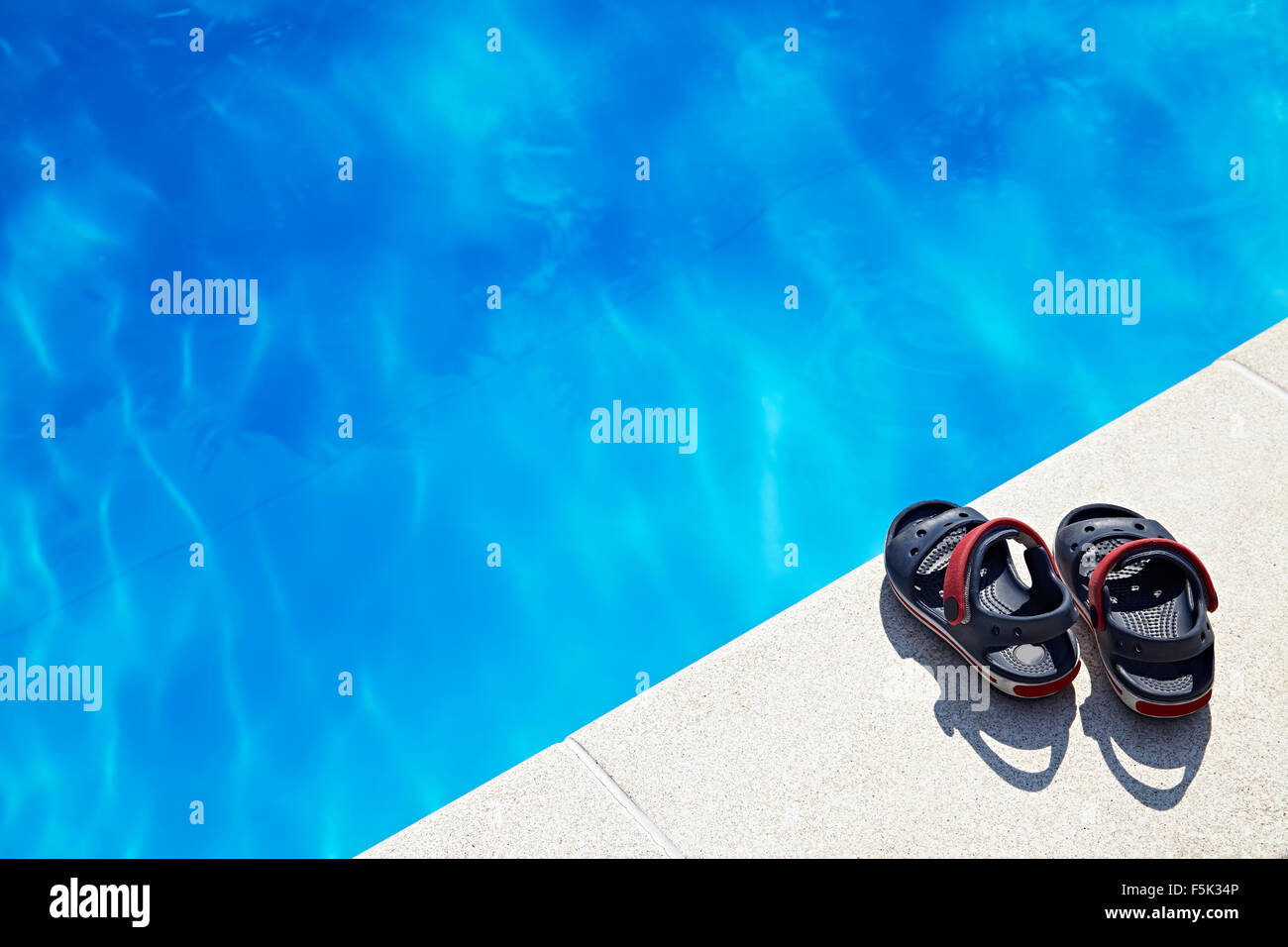 Pair of baby sandals at the swimming pool at sunny day. Copy space ...