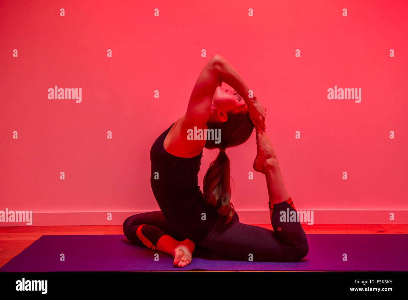 A beautiful girl in a yoga pose under brightly coloured lights Stock ...