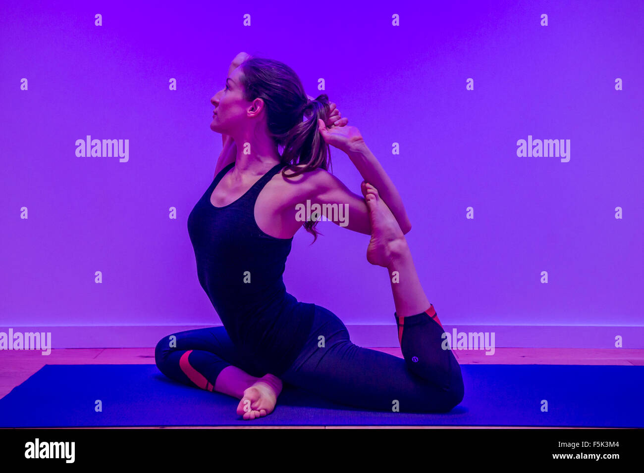 A beautiful girl in a yoga pose under brightly coloured lights Stock ...