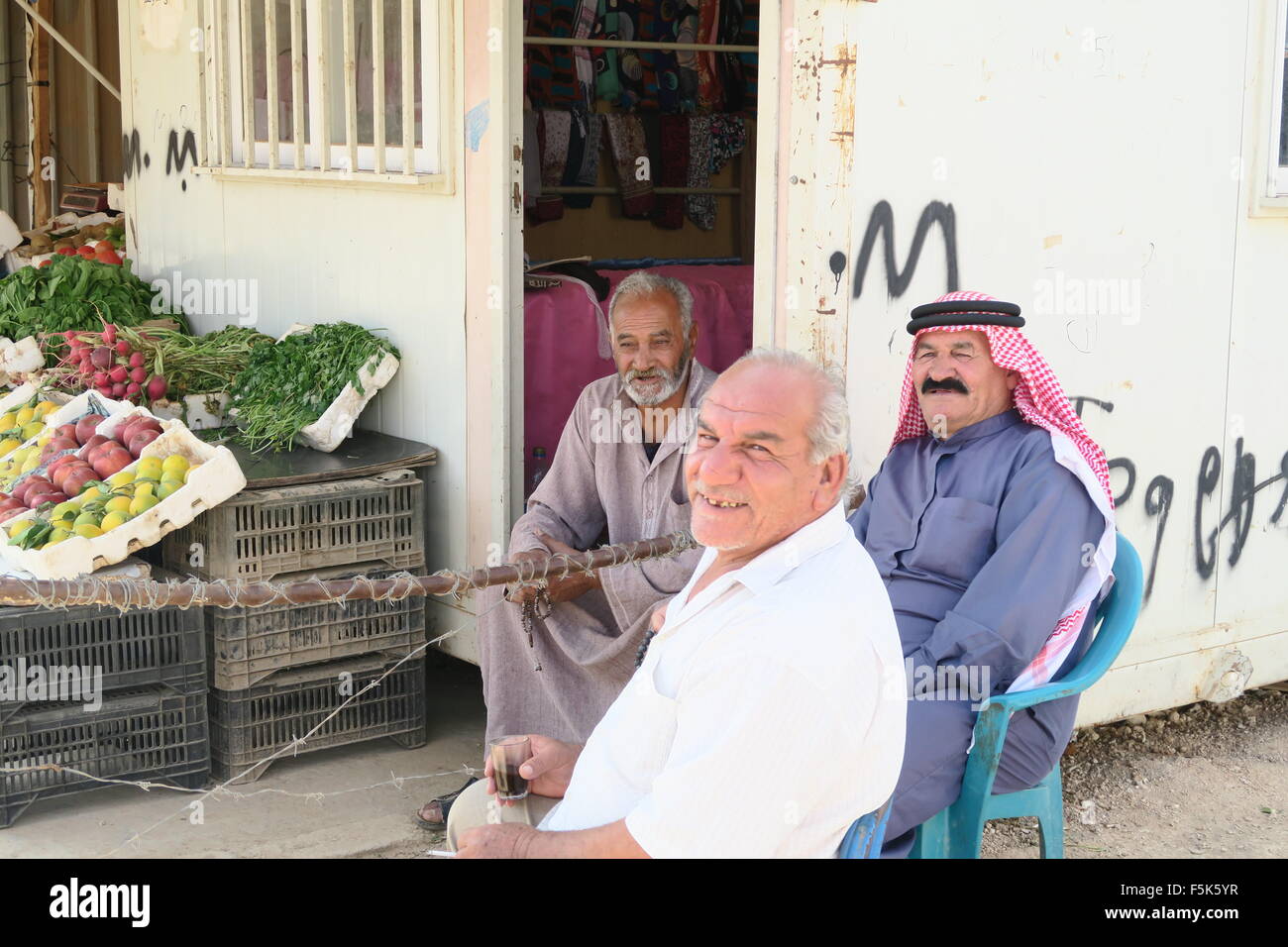 Three men from Syria and Afghanistan relax outside a fruit and ...
