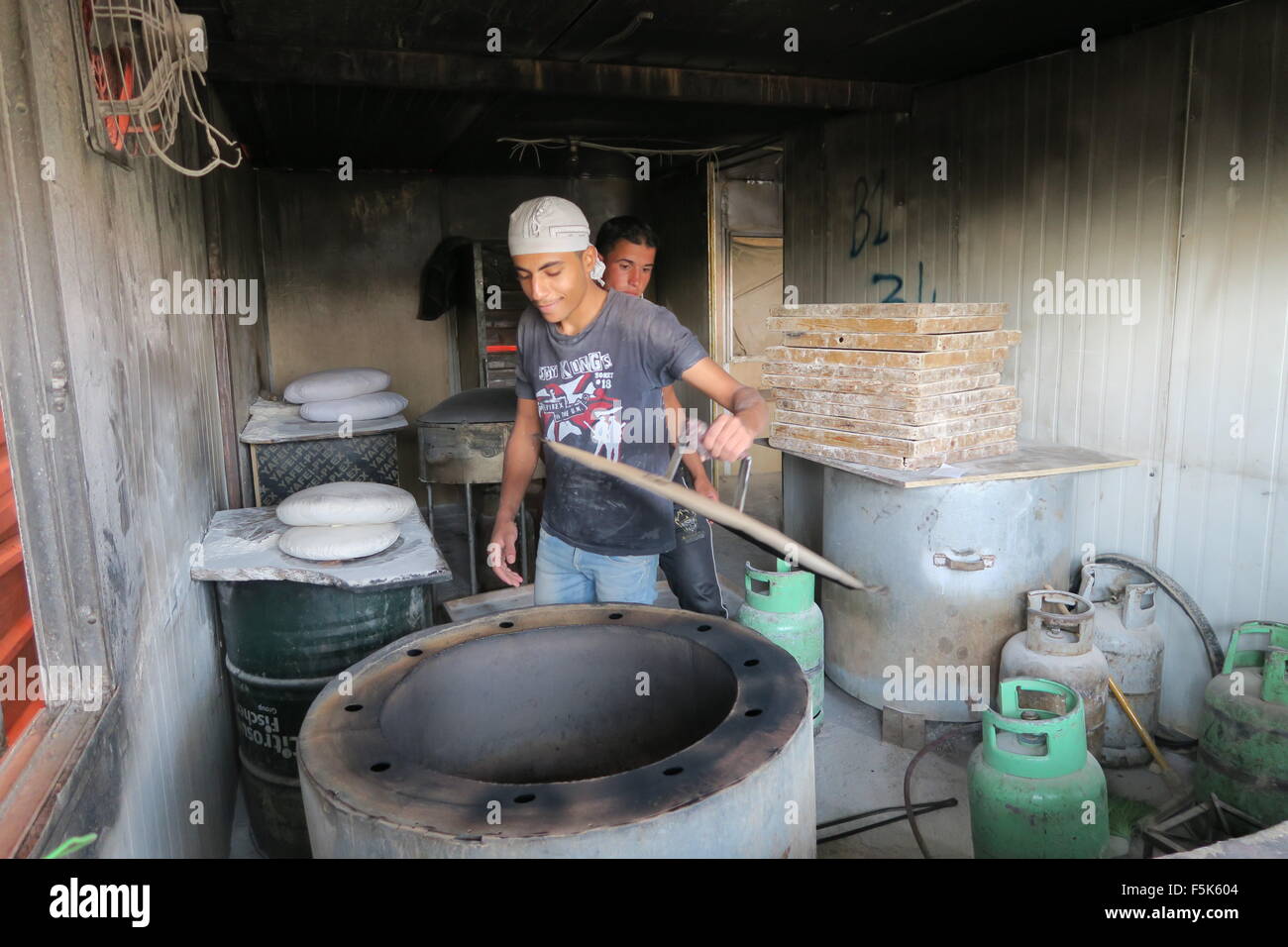 Syrian refugee bakers prepare bread in a traditional oven in the ...