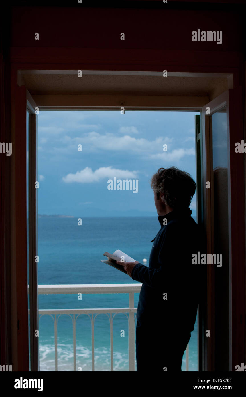 man standing in window frame reading Stock Photo - Alamy