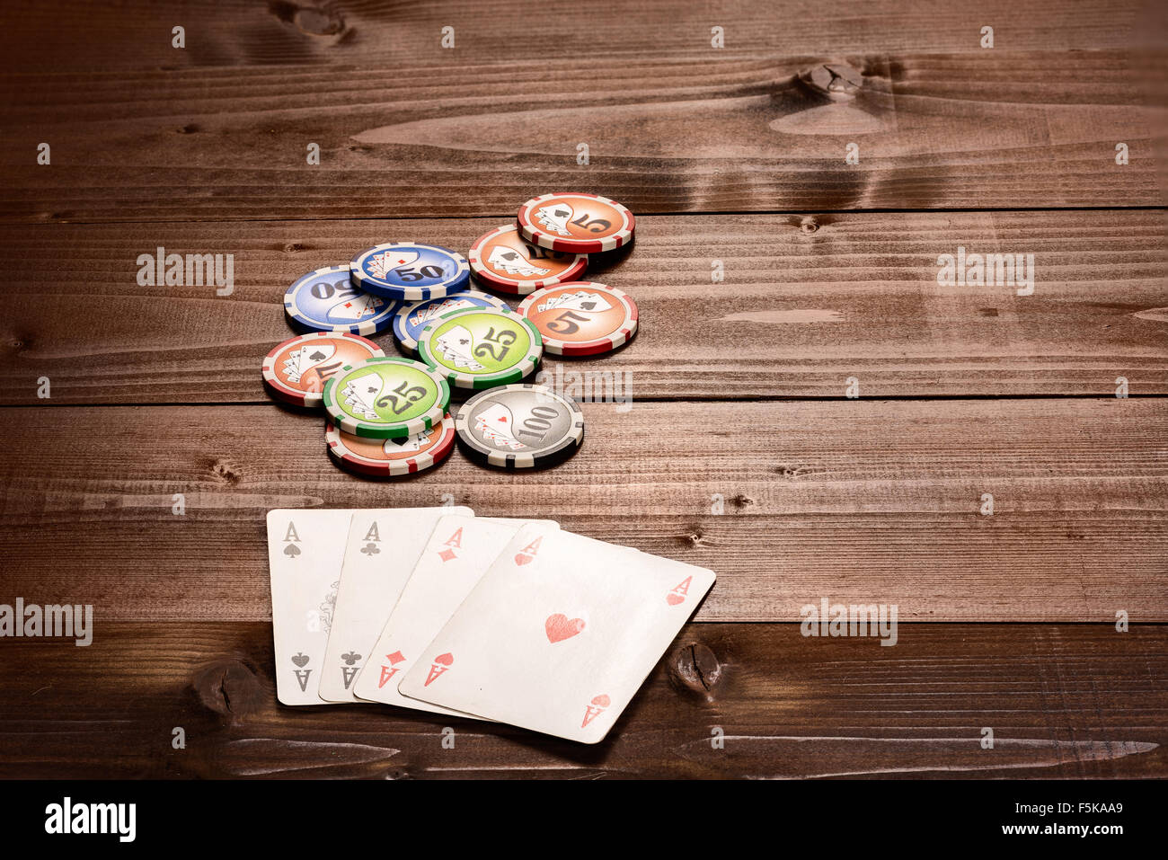 Four aces and chips, vintage poker game playing cards on a wood table ...