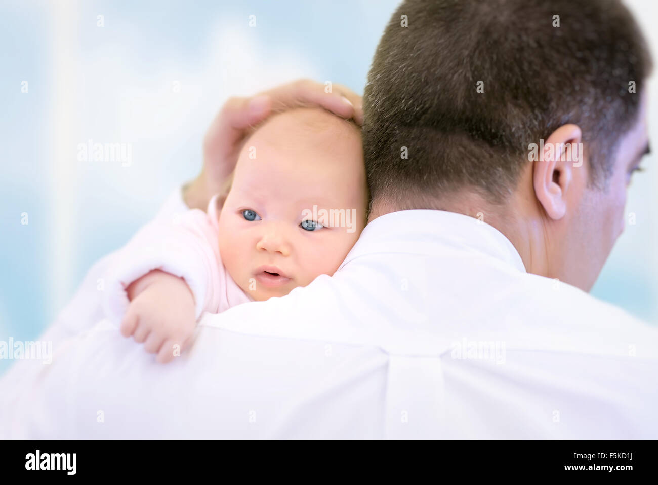 Back side of father holding little baby daughter on shoulder, enjoying ...