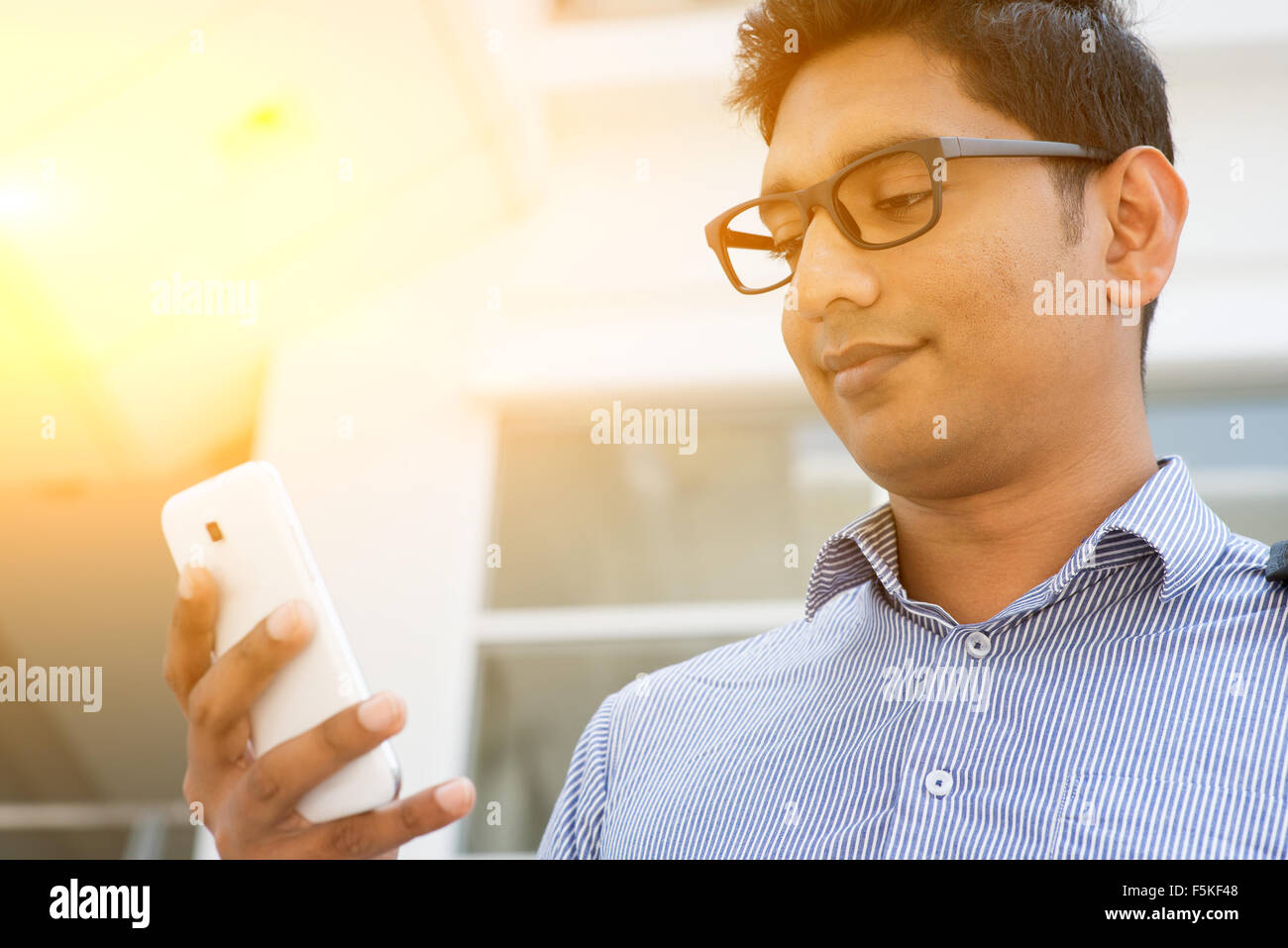 Asian Indian business people using smartphone, modern urban sunrise ...