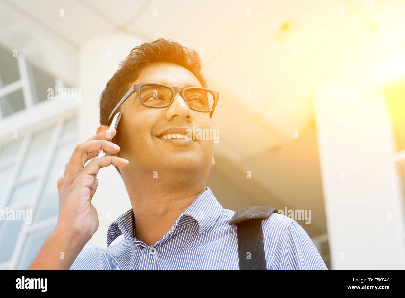 Indian businessman talking on phone in front modern office building ...