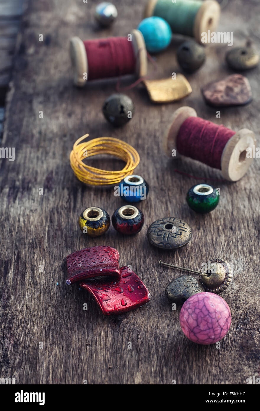 The spool of thread,beads and wire for needlework on wooden background ...