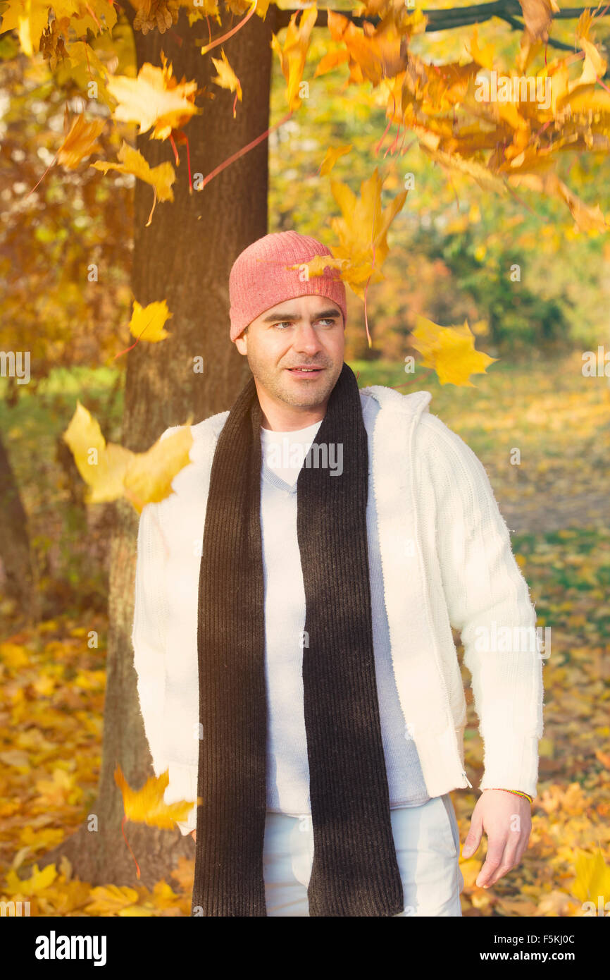 man standing by a tree in fall and leaves are falling down Stock Photo ...