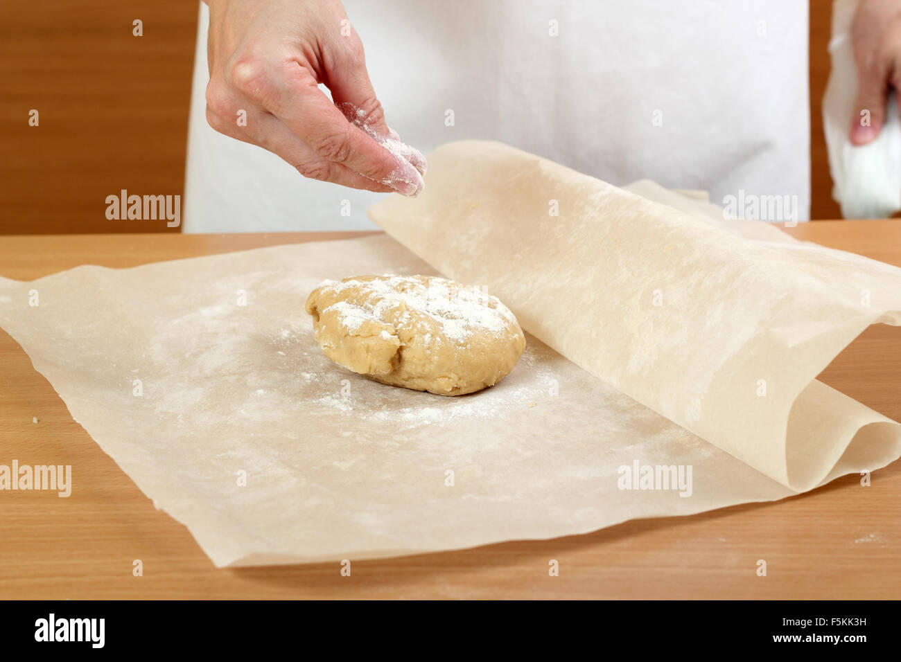 A baker rolling a dough between sheets of baking paper. Making Pastry ...