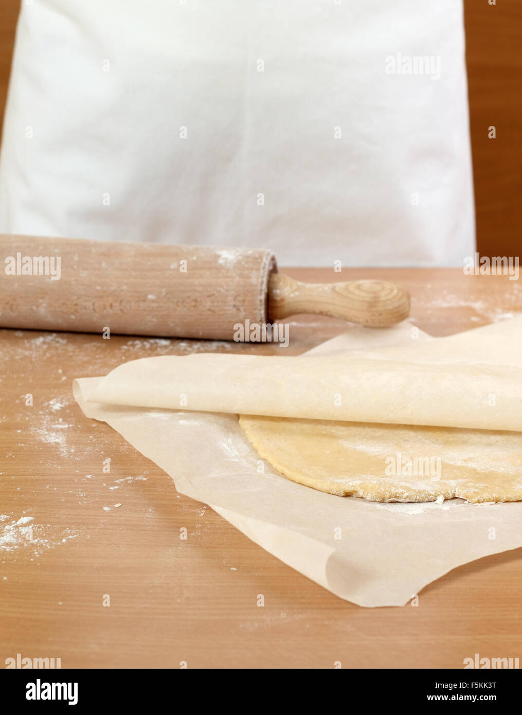 A baker rolling a dough between sheets of baking paper. Making Pastry ...