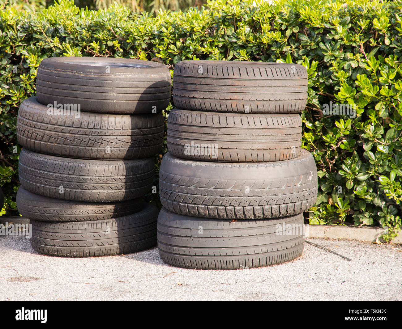 Pile of used worn out tyres green bushes in background Stock Photo - Alamy