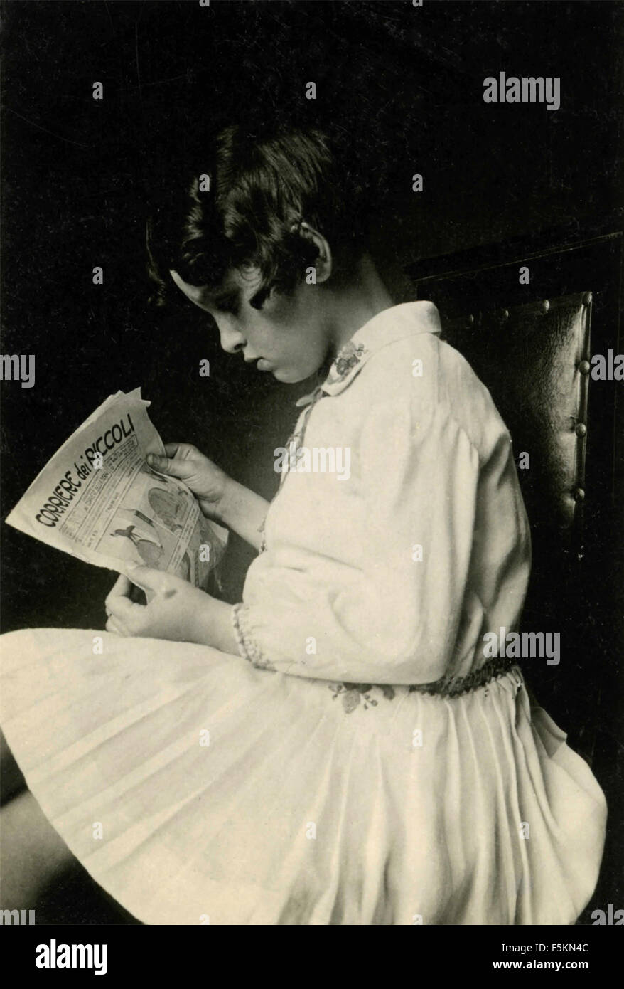 A little girl dressed in white reads the Corriere dei Piccoli, Italy ...