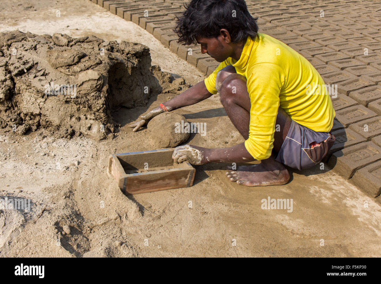 A young guy worker is filling a form with clay as a step to produce ...