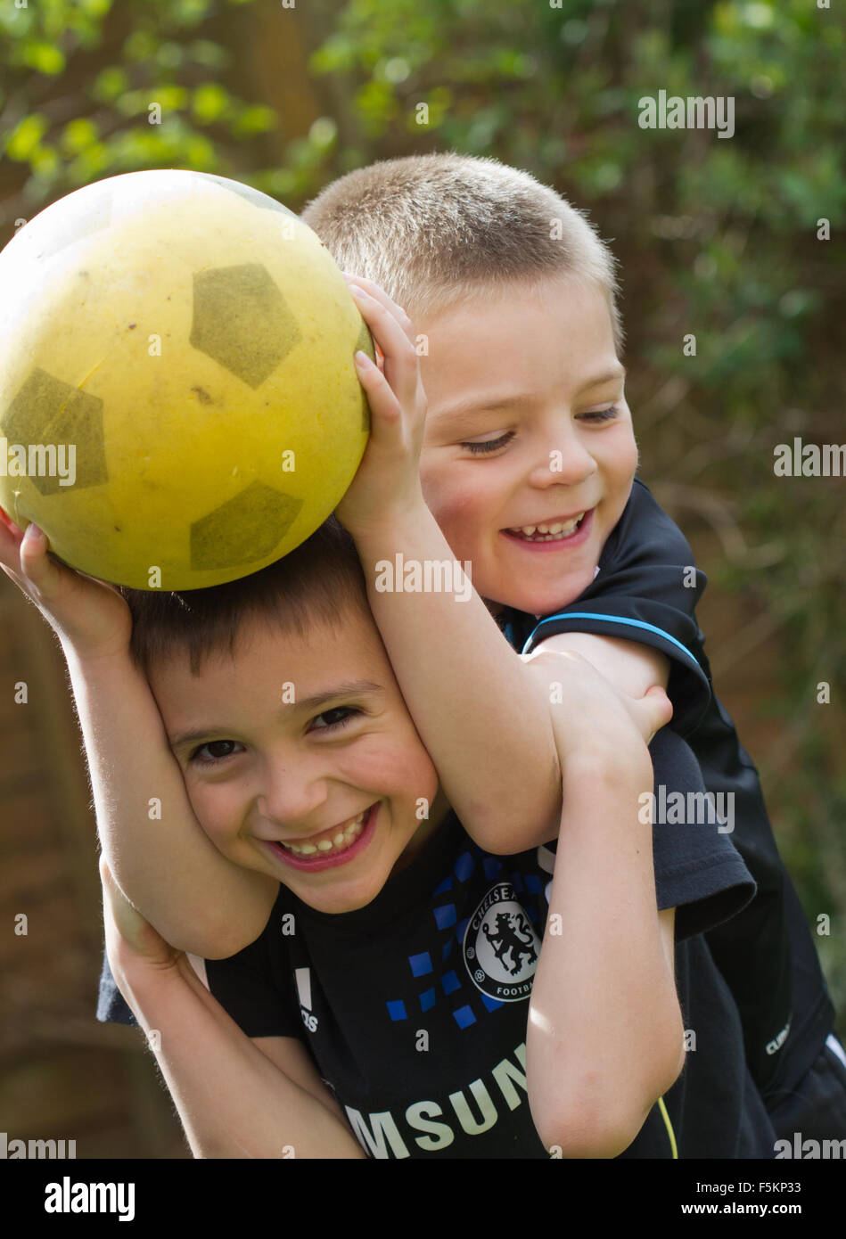 Boys playing with a ball having a piggy back ride carried lift Stock ...