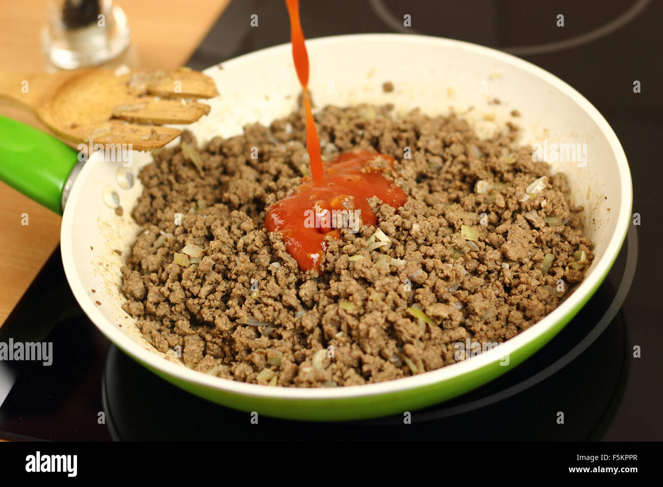 Pouring chili sauce into ground beef. Making enchilada tortilla with ...