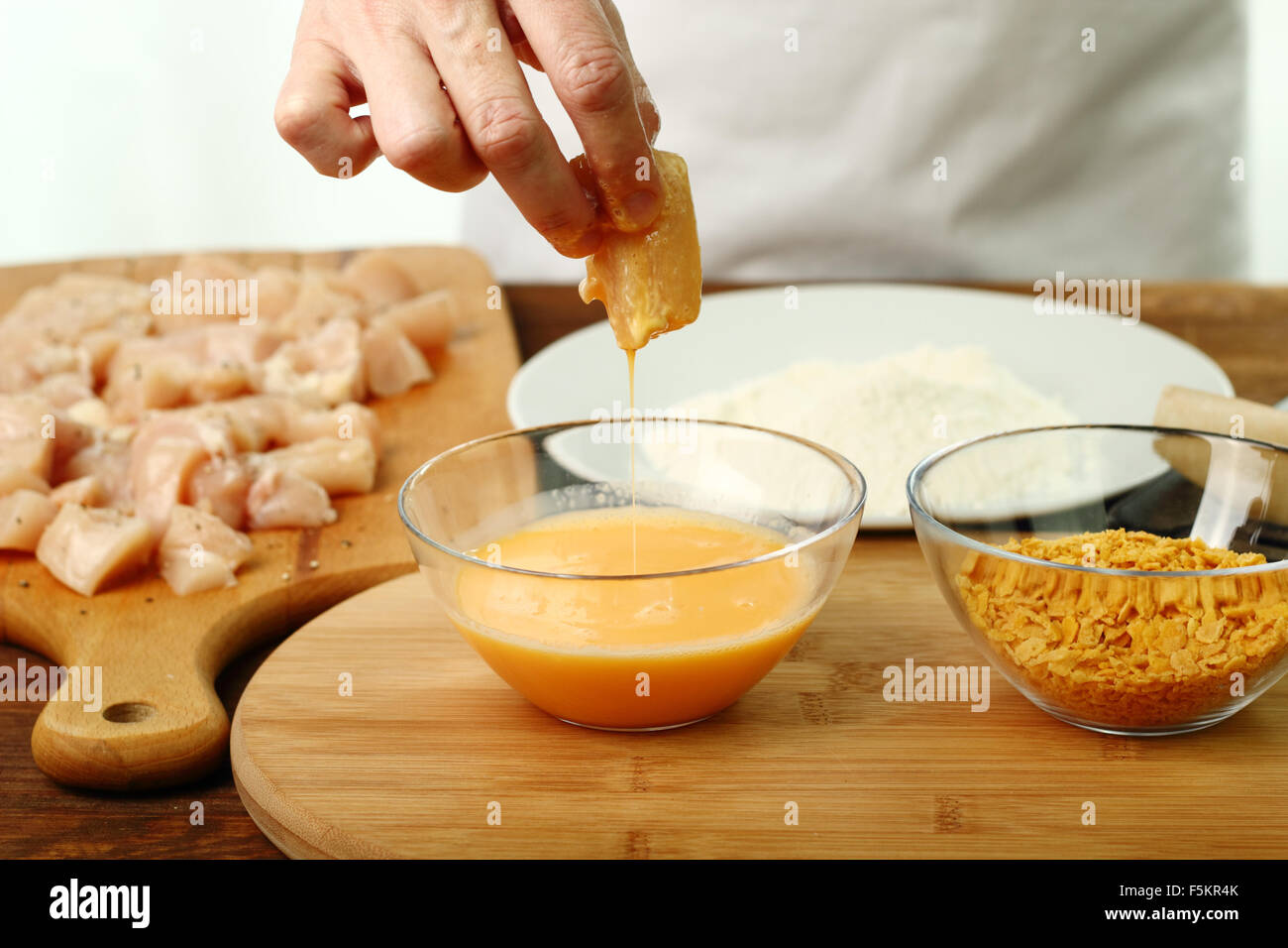 Freshly egged chicken fillet. Making oven baked corn flake crumbs ...