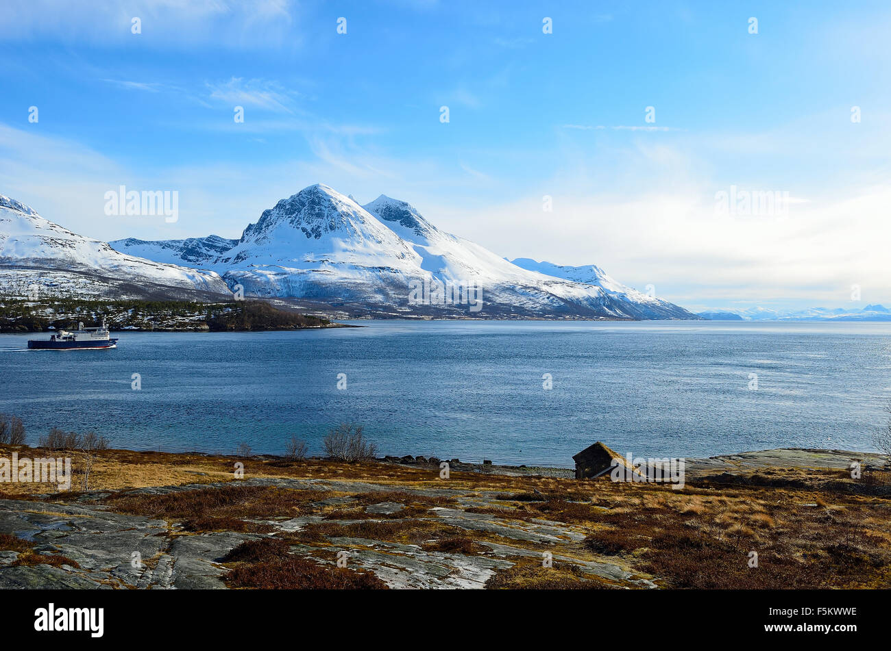 Majestic snow covered mountain with a blue sky and ocean in front with ...