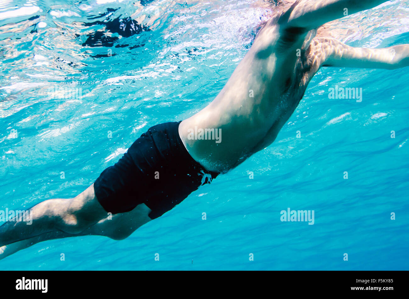 A male body underwater swimming in a clear blue mediterranean sea and ...