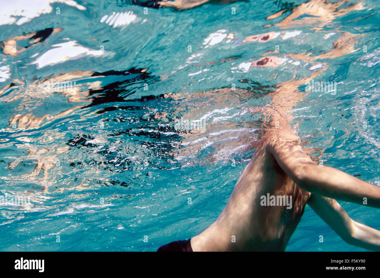 A male body underwater swimming in a clear blue mediterranean sea and ...
