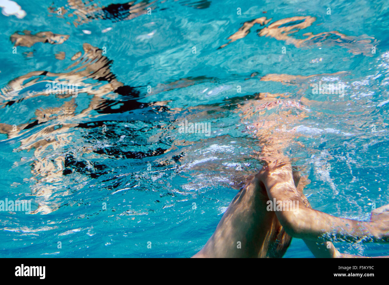 A male body underwater swimming in a clear blue mediterranean sea and ...