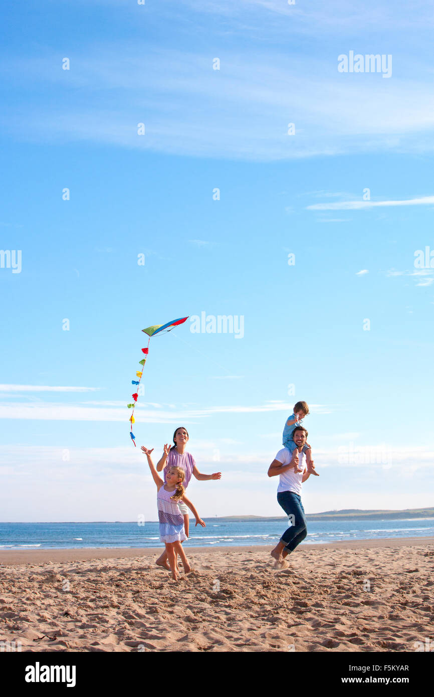 Family of four flying a kite on the beach together Stock Photo - Alamy