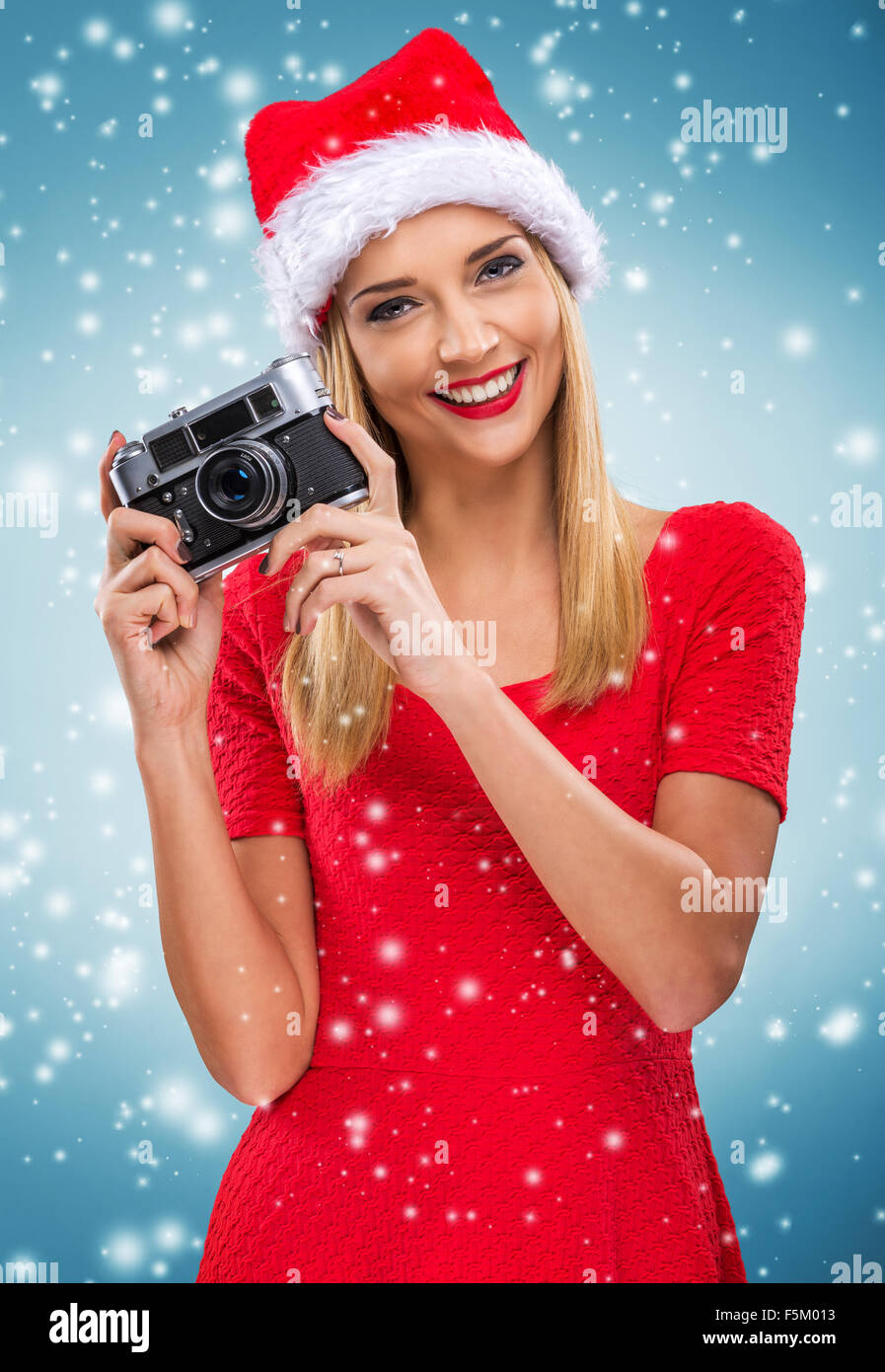 Beautiful santa woman holding camera, snowfall background Stock Photo ...