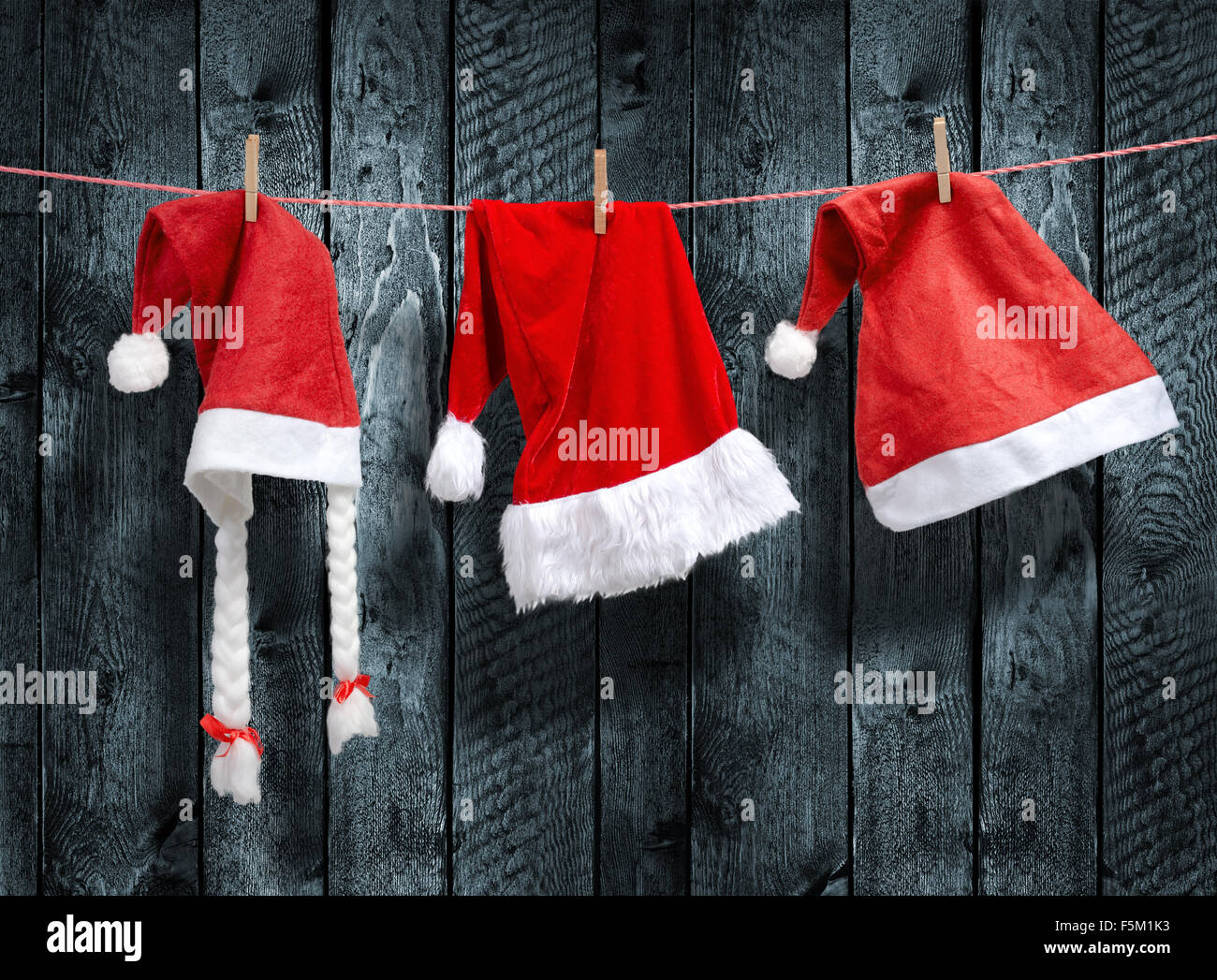Three Santa Claus hat hanging on a clothesline Stock Photo - Alamy