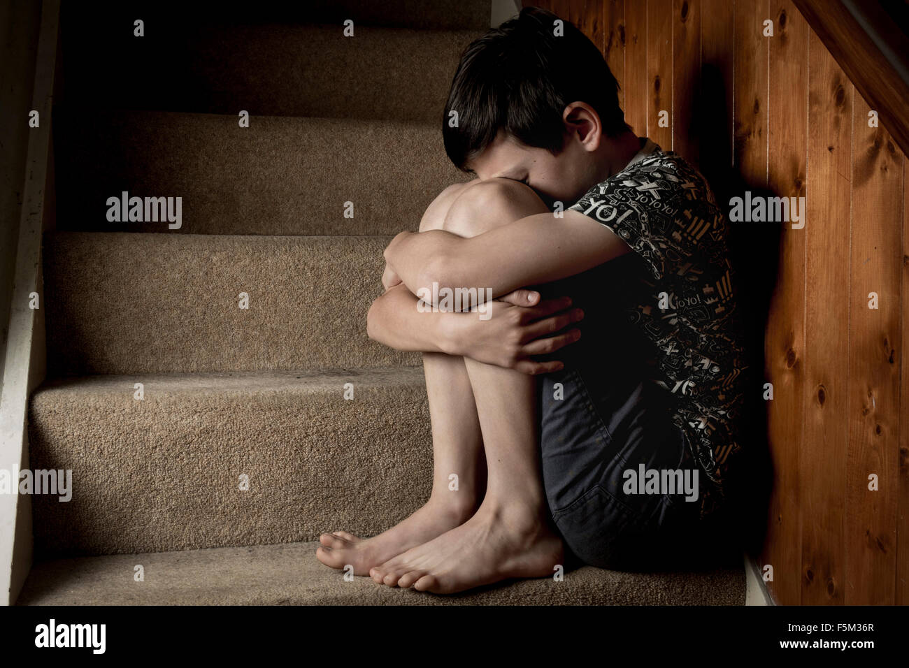 Sad, bullied or abused boy sitting on the stairs Stock Photo - Alamy