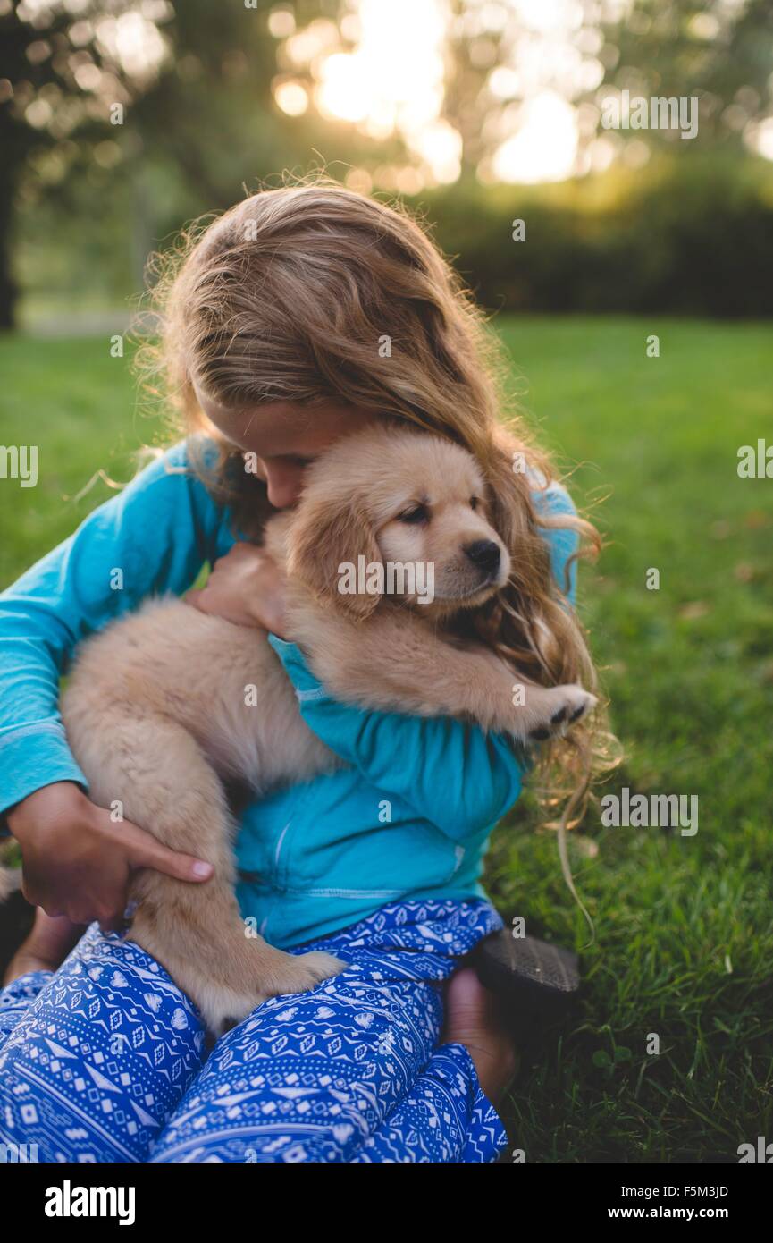 Girl hugging puppy in garden at sunset Stock Photo - Alamy