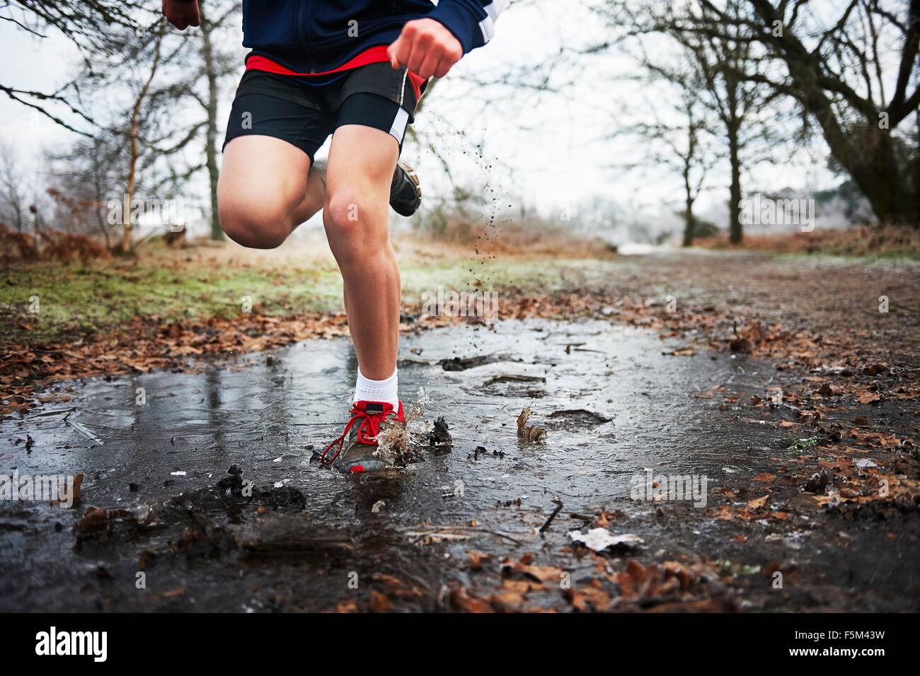 Front view of teenage boy running through puddle Stock Photo - Alamy