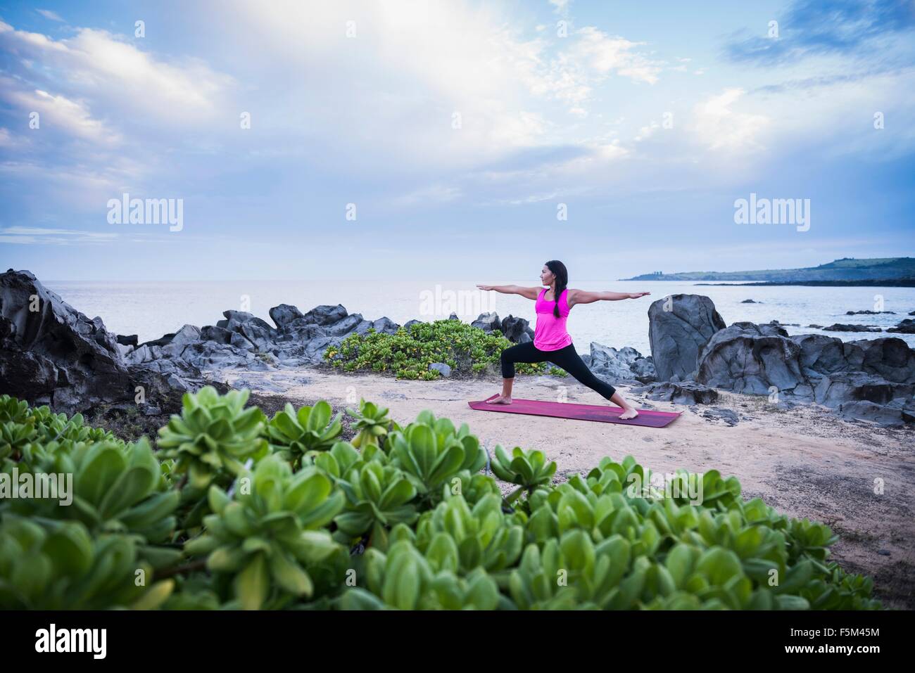 Woman practicing warrior yoga pose on beach, Hawea Point, Maui, Hawaii ...