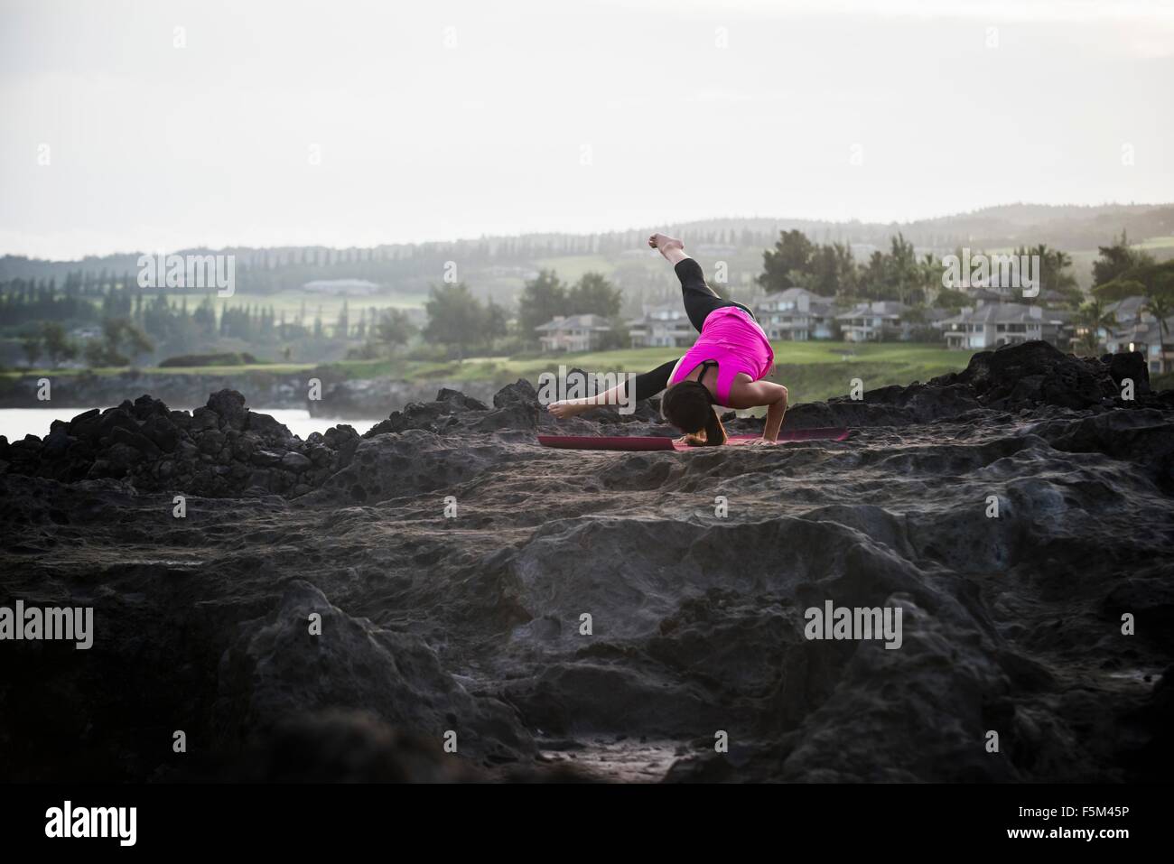 Woman at coast practicing yoga balancing on hands, Hawea Point, Maui ...