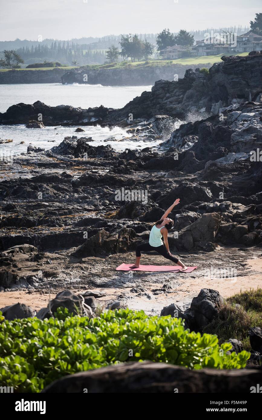 Woman practicing warrior pose on beach, Hawea Point, Maui, Hawaii, USA ...